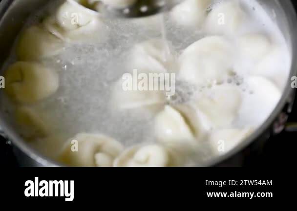 Ravioli boiling in water with spices Close-up of dumplings on a skimmer ...