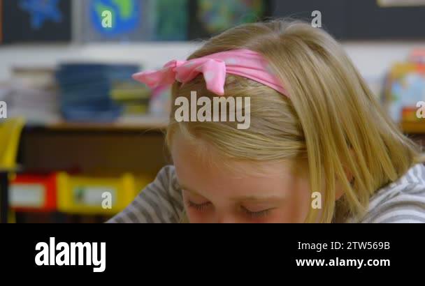 Front view of Caucasian schoolgirl sleeping on desk in classroom at ...