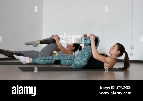 In the gym during the pilates exercise lying on the gym mats two girls ...