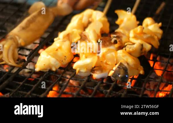 Night market, Pattaya, Jomtien. Squid grilling on a grill. Thai cuisine. Asian exotic dishes on ...