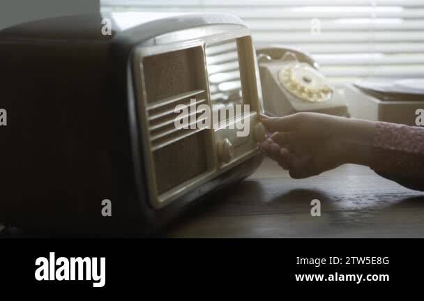Woman tuning a vintage radio and searching for station frequencies, she ...