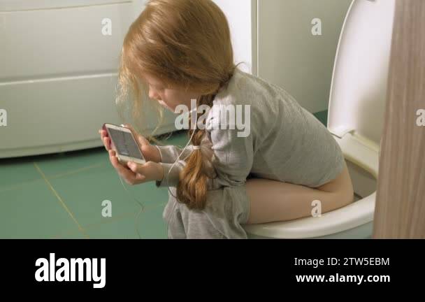little girl sits on the toilet and uses the phone Stock Video Footage ...
