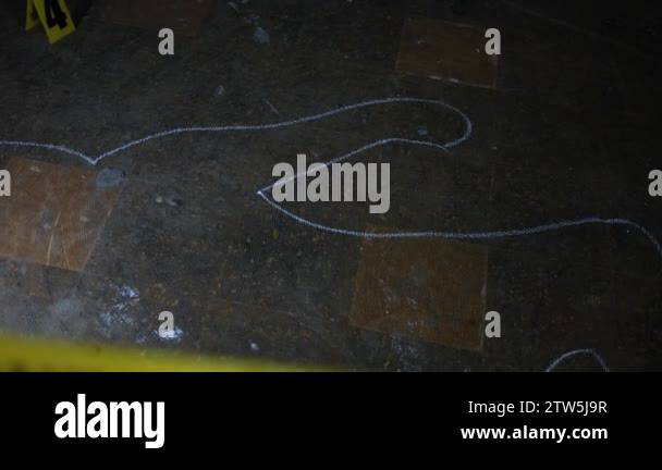 Handheld camera move over yellow police tape over chalk outline at ...