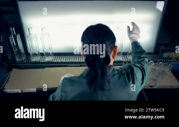 Female factory worker is throwing away defective vitreous bottles from ...