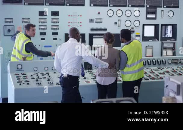4K Workers in power plant control room looking at control panel and ...