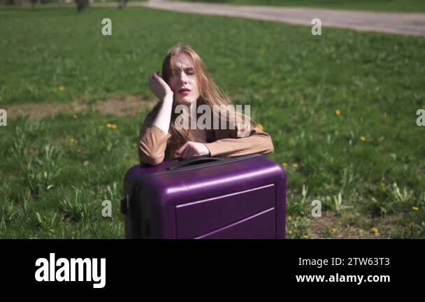 Sad traveler missed her flight and bus - Sitting on her luggage ...
