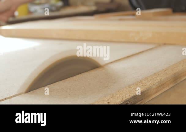 young man cuts a wooden board with a circular saw blade, a workshop ...