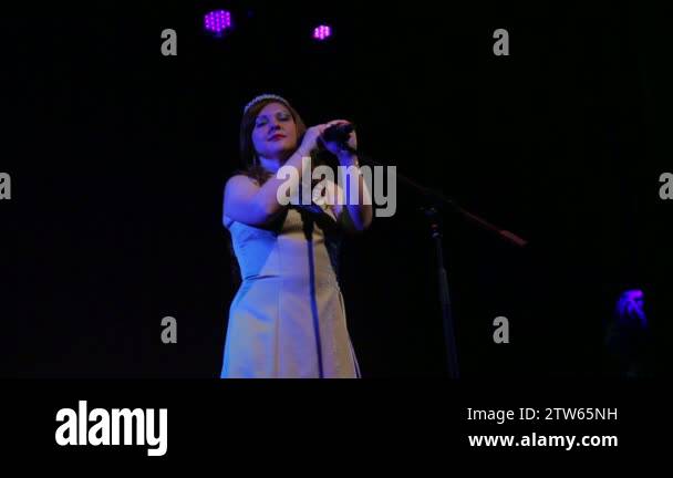 A young red-haired singer sings on stage with a microphone giving a ...