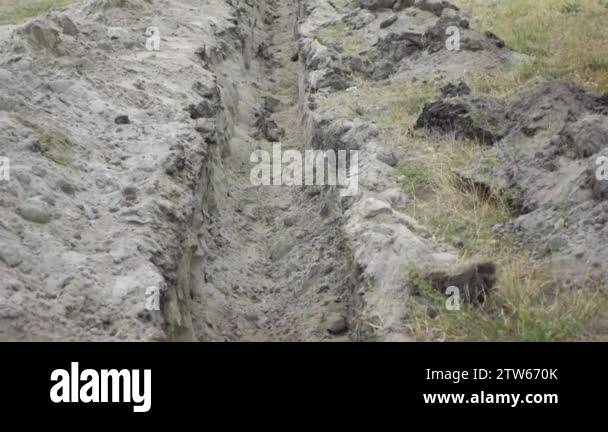 Two little girls jump over an earthen ditch, dug for laying pipes Stock ...