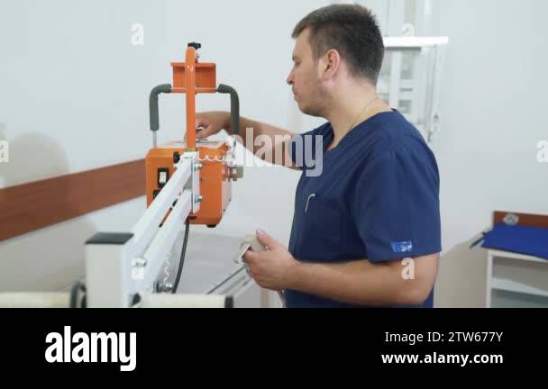 Male doctor adjusts the X-ray machine using a remote control. man in ...
