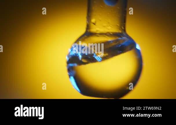 Distilled water with blue tints is shaken in a round bottom flask in a ...