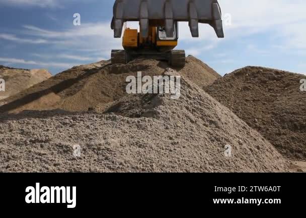 Excavator is preparing pile of sand for loading in truck on building ...
