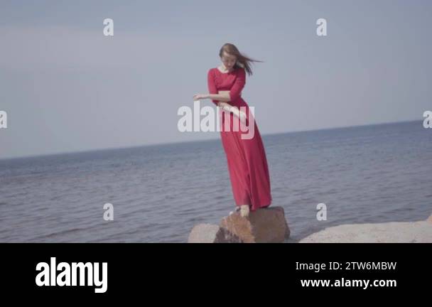 Delicate graseful woman in red long dress dancing raises hands on the ...