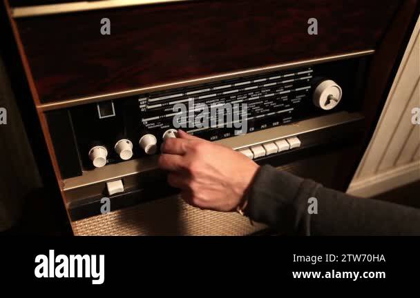 Retro radio, the man changes the frequency on the old radio receiver ...