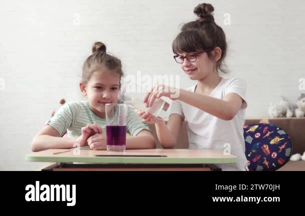 children conduct chemical experiments at home. two little girls observe ...