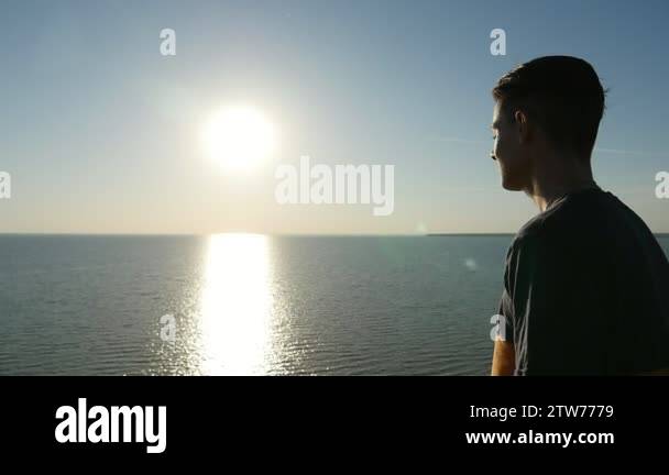 Emotional young man stands on the Black Sea coast at splendid sunset in ...