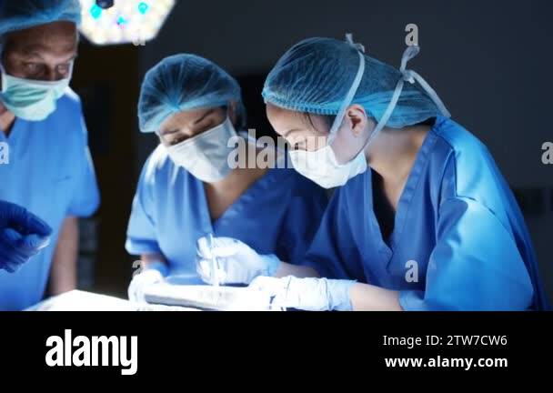 4K Team of surgeons in operating theater performing operation on a ...