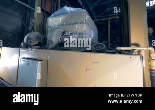 Industrial machine is adjusting wrapping material around a set of boxes ...
