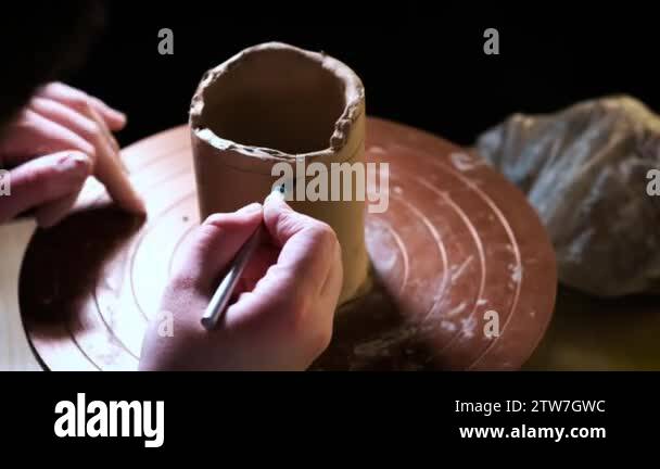 Close up of hands working clay on potters wheel. Potter shapes the clay ...
