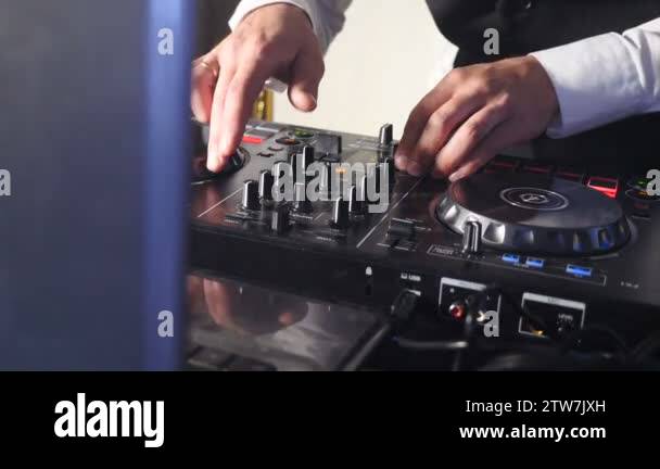 DJ behind console, on stage, mixing tracks in atmospheric dance party ...