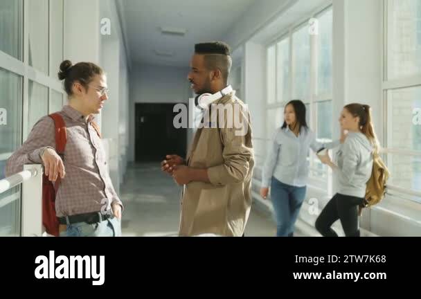 Multi-ethnic group of students talking in corridor of university having ...