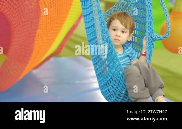 sad boy three years old, swinging on a swing alone in the childrens ...