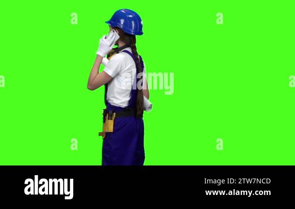 Engineer girl standing with her back holding a drawing and talking on ...