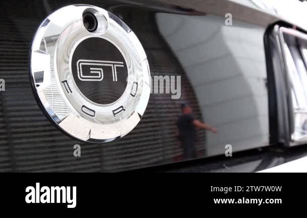 Ford Mustang GT logo on a black car. In a reflection of a luxury car ...