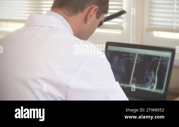 Doctor looking at computer screen while patient moving in mri machine ...