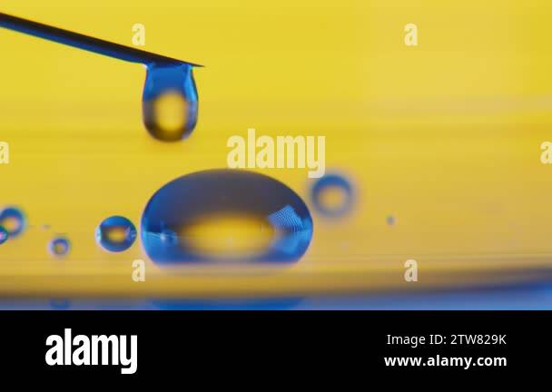 Transparent drops of water plash from a syringe forming a small pool A ...