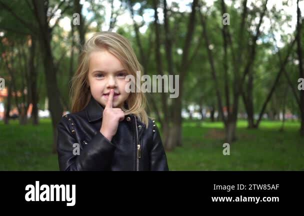 Cute little girl making a hush sign in a park Stock Video Footage - Alamy