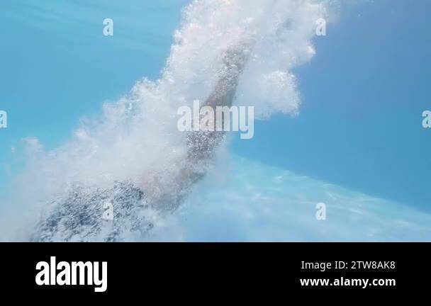 Male swimmer dive on blue water in swimming pool at start slow motion ...