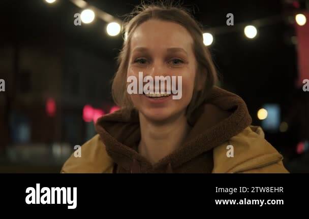Front footage of young girl on the night street smiling and playfully ...