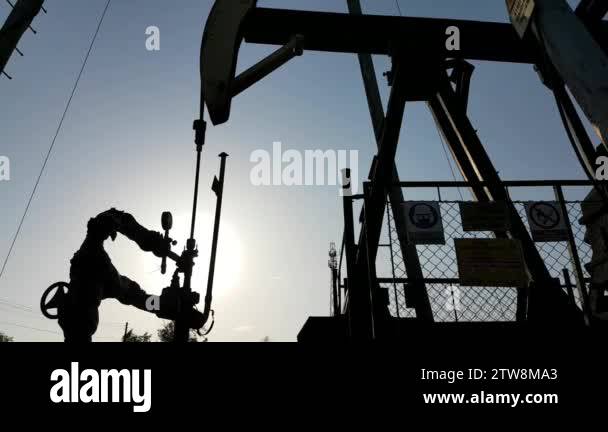 Siluette of operating oil pump station in sunset. Tansport and distribution of oil. Technology ...