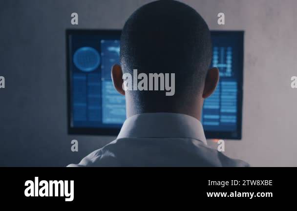 Back view of man programmer in white shirt working at computer in the ...