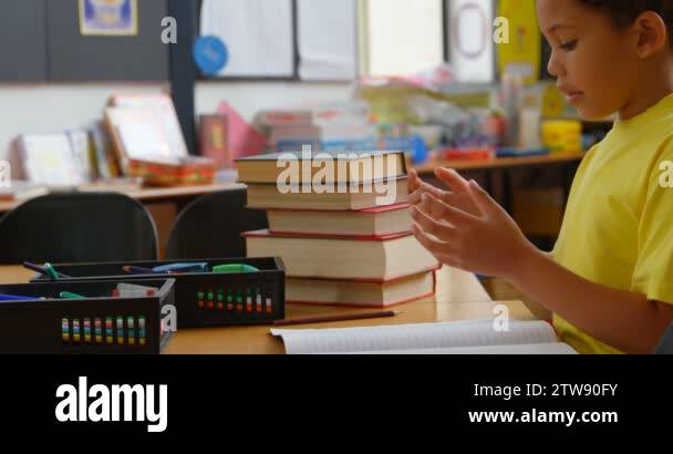 Side view of African American schoolboy counting with his finger at ...