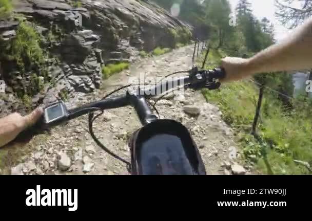 POV man riding e-bike on rocky trail near lake.Mtb action cyclist exploring path near mountains ...