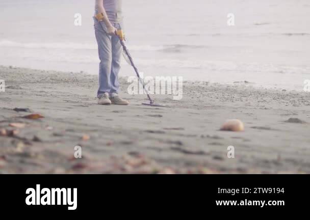 Man is finding valuables in the sand on the sea beach using metal ...