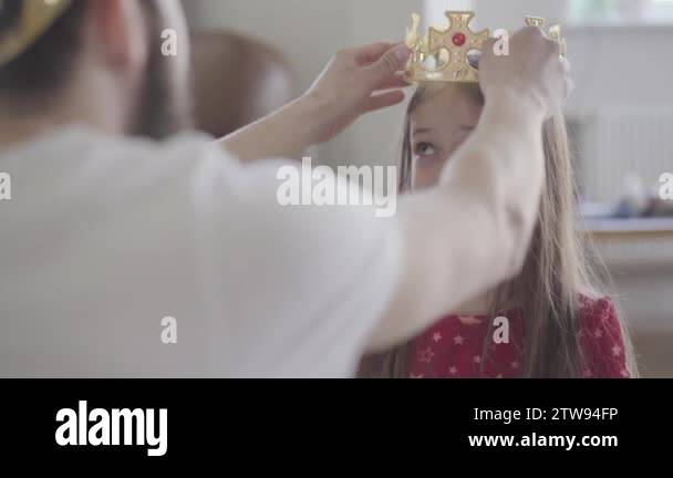 Young father putting the crown on the head of his little daughter ...