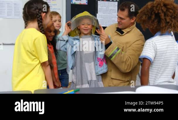 Front view Caucasian male firefighter teaching schoolkids about fire ...