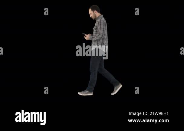Young smart casual man walking and reading message on cell phone, Alpha ...