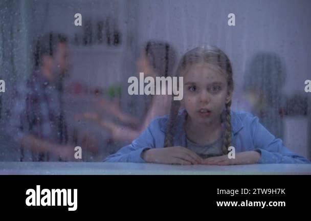 Little girl crying behind rainy window, suffering from parents ...