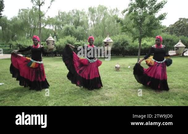 Three african women dancing a folk dance in traditional costumes with ...