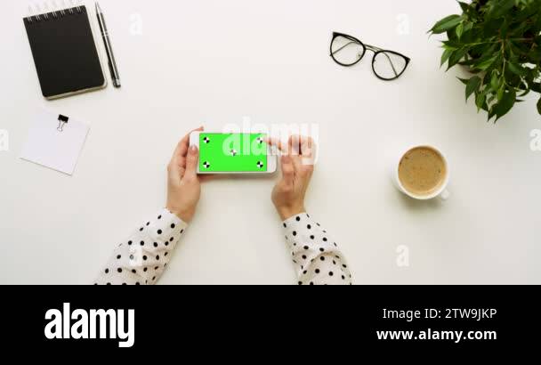 Top view on the office desk and white smartphone with green screen and ...
