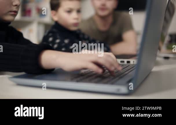 Kids arms typing somethingon laptop keyboard with two unrecognizable ...