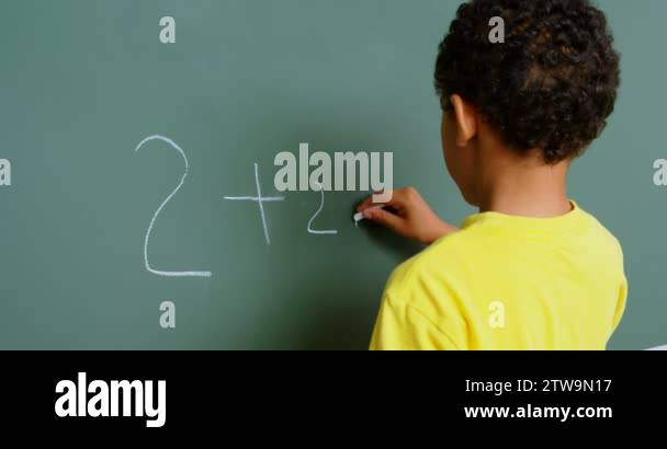 Rear view of African American schoolboy solving math problem on ...