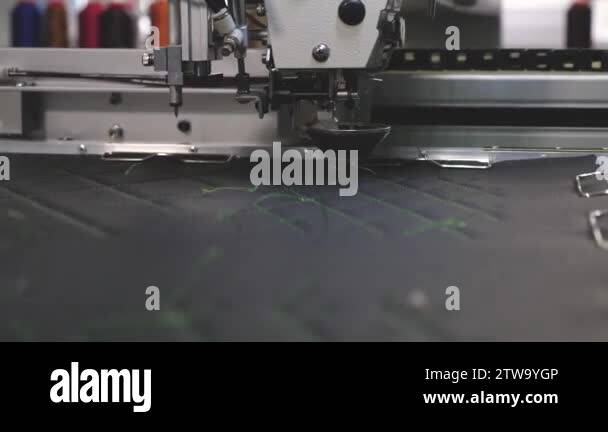 Robot sewing machine. an automated machine embroidery pattern with red threads on a black cloth ...