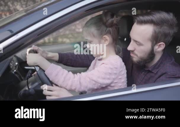 Little girl sitting on fathers lap in the car close up. The child is ...