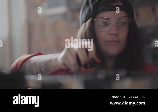 Portrait skill woman in a cap and protective glasses with pierced lip ...