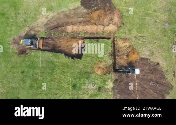top down of bulldozer and excavator digging pit according to marking on ...